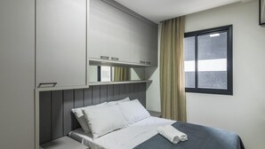 Quarto de hotel moderno com cama, mesa de cabeceira, prateleira embutida e janela com cortinas.