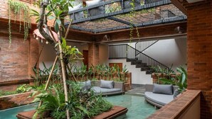 Uma área ampla de piscina interna com uma ilha central, rodeada por assentos e vegetação exuberante.