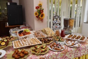 Uma mesa de buffet com diversos alimentos, incluindo doces, frutas e sobremesas.