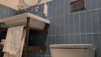 Uma casa de banho com uma pia branca, um espelho, uma sanita e paredes revestidas a azulejos azuis.