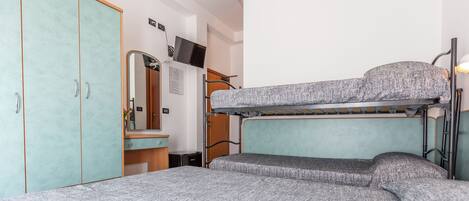 Uma cama beliche com colchão cinza, um guarda-roupa com porta azul claro e uma pequena escrivaninha com espelho.