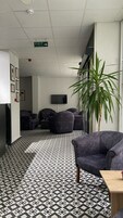 Um interior moderno com piso estampado, uma TV de tela plana na parede e uma planta grande em vaso.