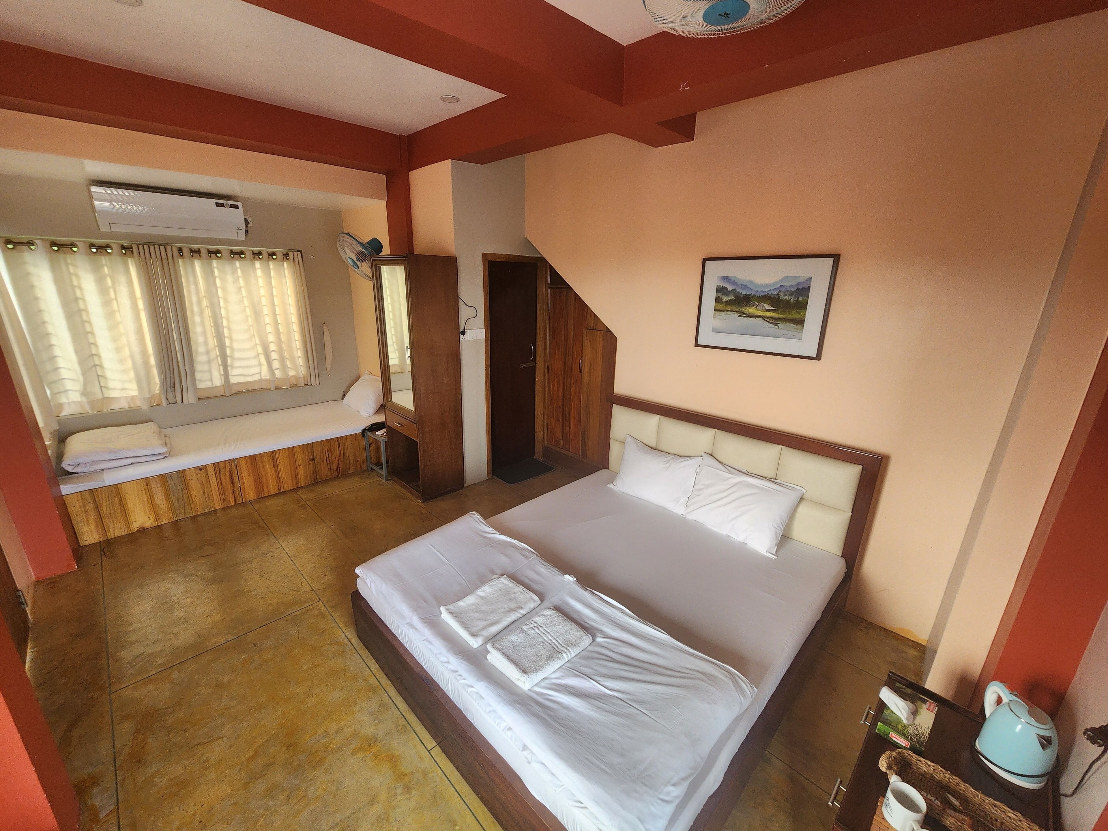 Quarto com cama, janela com cortinas, ar condicionado, guarda-roupa de madeira e um quadro na parede.