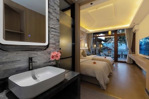 Quarto de hotel moderno com um espelho grande, uma banheira, uma cama com duas almofadas e uma televisão.