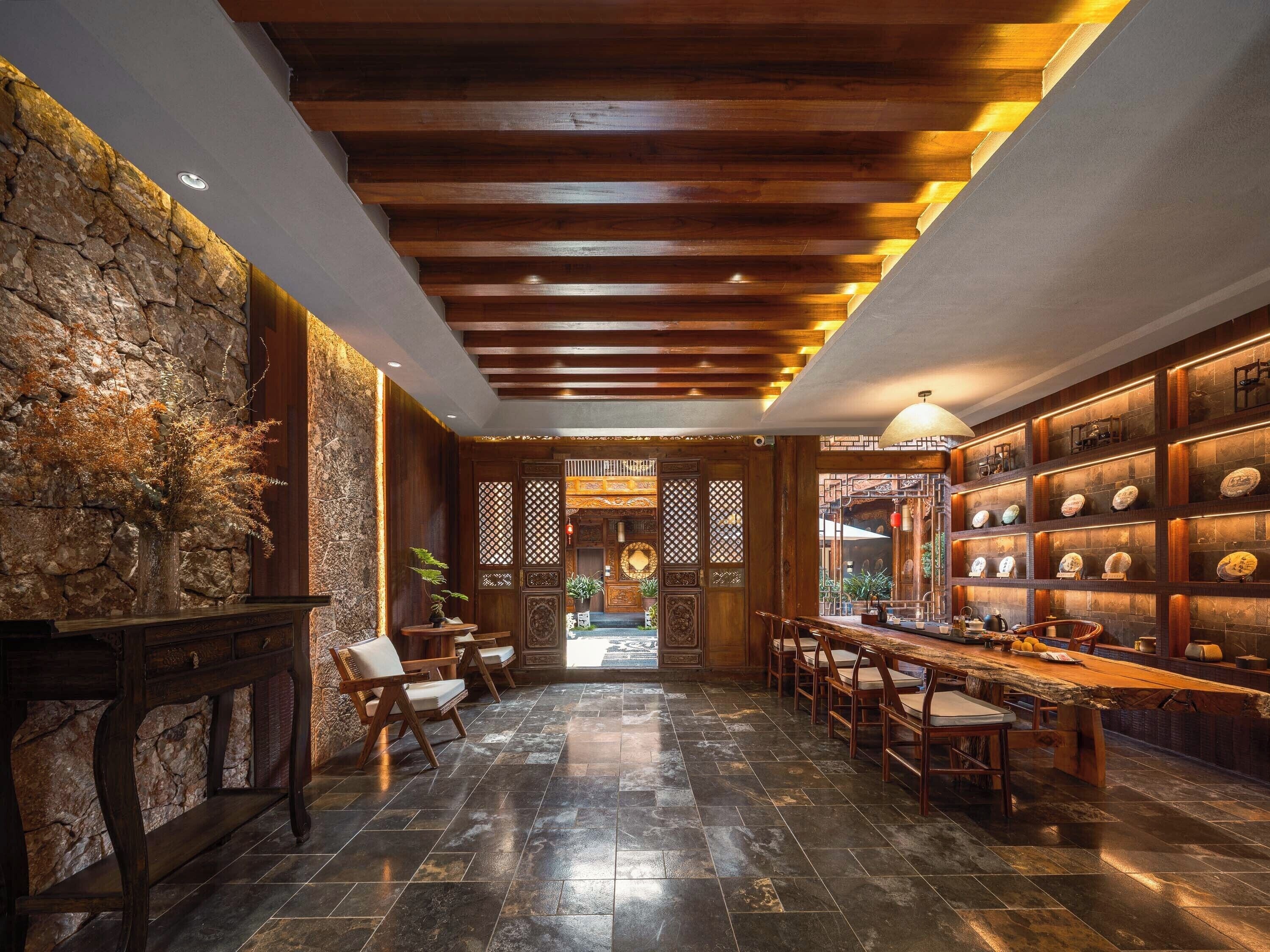 Um interior tradicional com parede de pedra, vigas de madeira no teto e chão de azulejos.