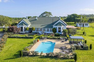 Uma casa grande com piscina, jardim e área de estar externa.