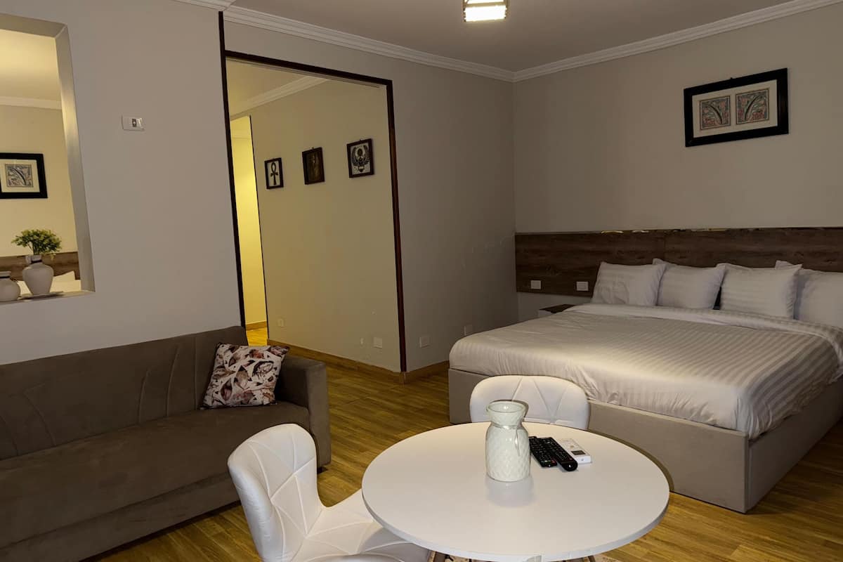 Um quarto moderno com cama, sofá, mesa de centro e espelho.