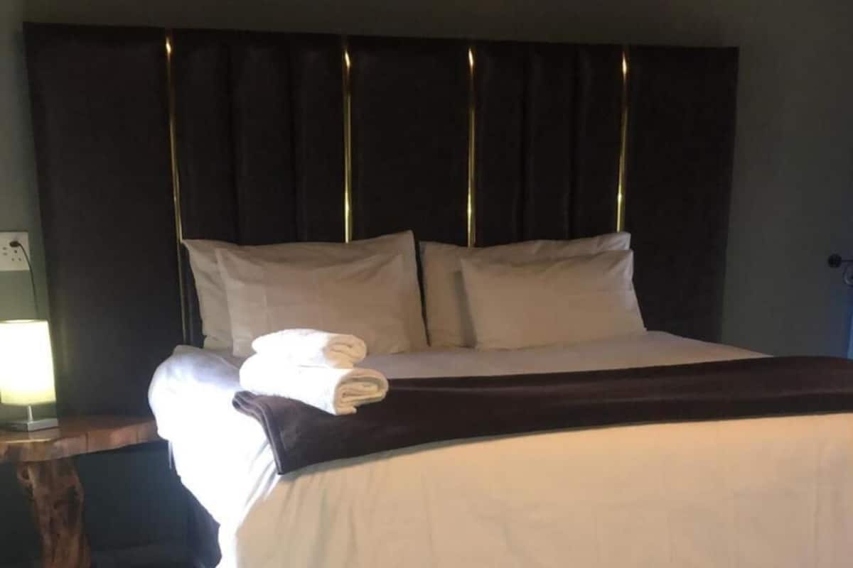 Uma cama bem arrumada com lençóis brancos e uma cabeceira escura.