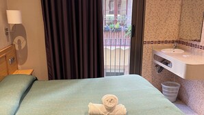 Quarto de hotel com cama, banheiro com pia e vista para a varanda externa.