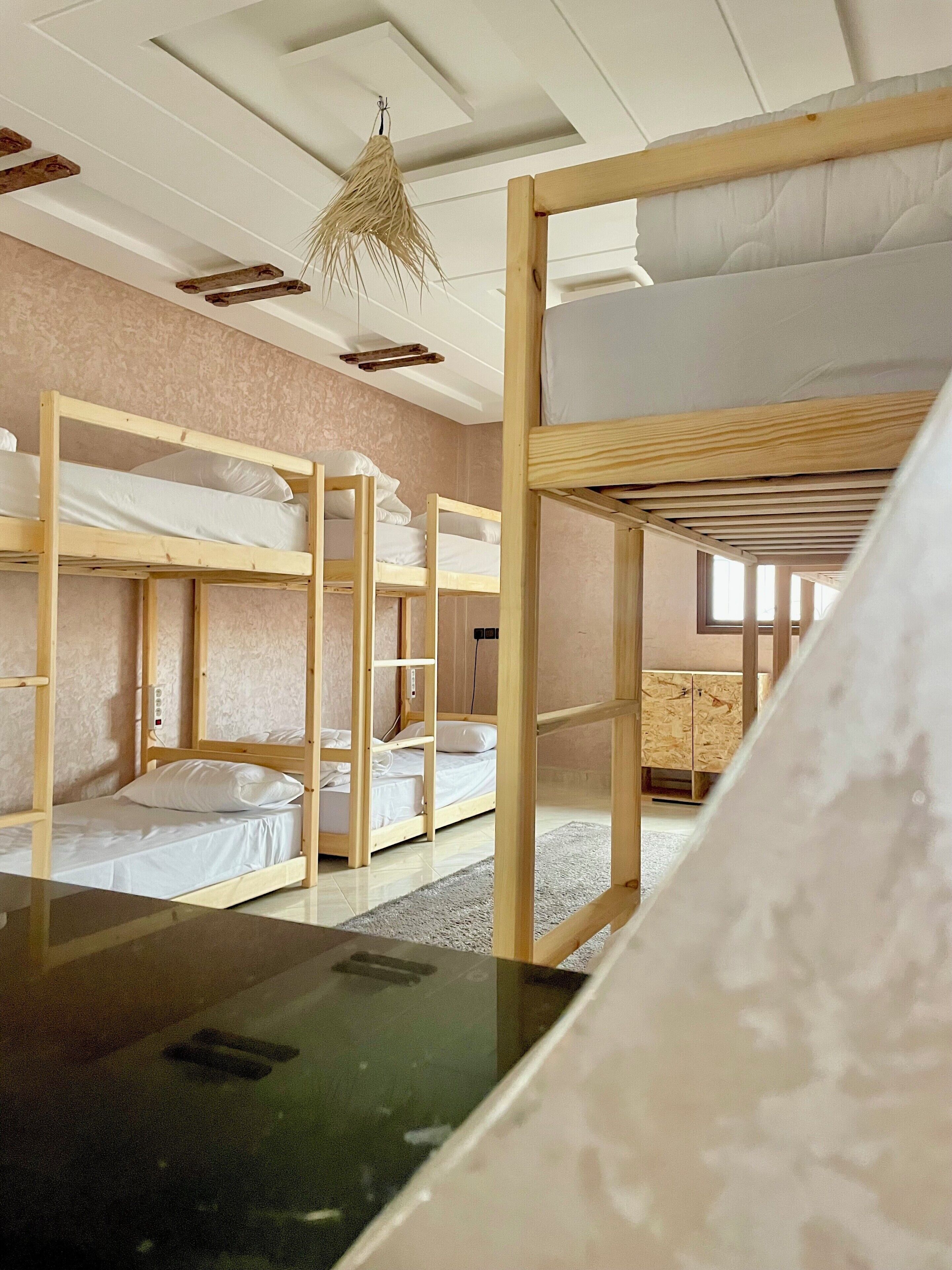 Quarto com beliches, ventoinha no teto e tomada visível.