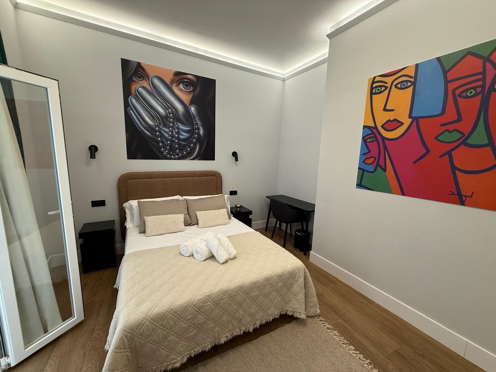 Um quarto moderno com uma cama, uma escrivaninha e duas pinturas nas paredes.