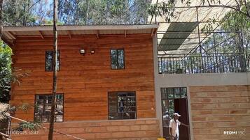 Uma cabana de madeira com várias janelas e uma porta, rodeada por árvores.
