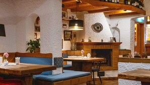 Um interior rústico com bancos de madeira, lareira e paredes de pedra.