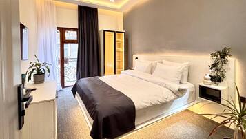 Quarto moderno com uma cama grande, uma mesa de cabeceira, um vaso de planta e vista para o exterior.