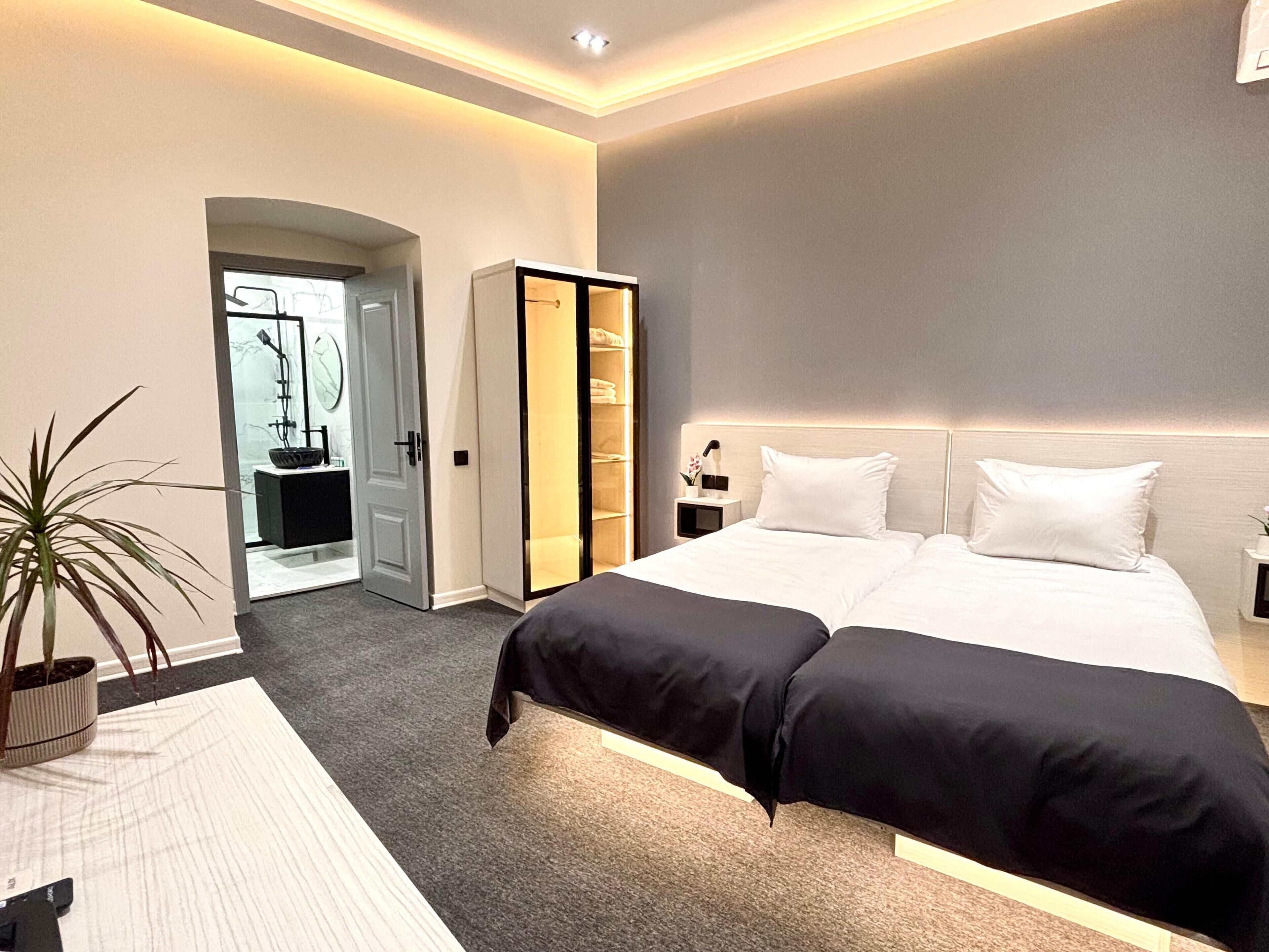 Quarto de hotel moderno com uma cama grande, um guarda-roupa e uma escrivaninha com uma planta.