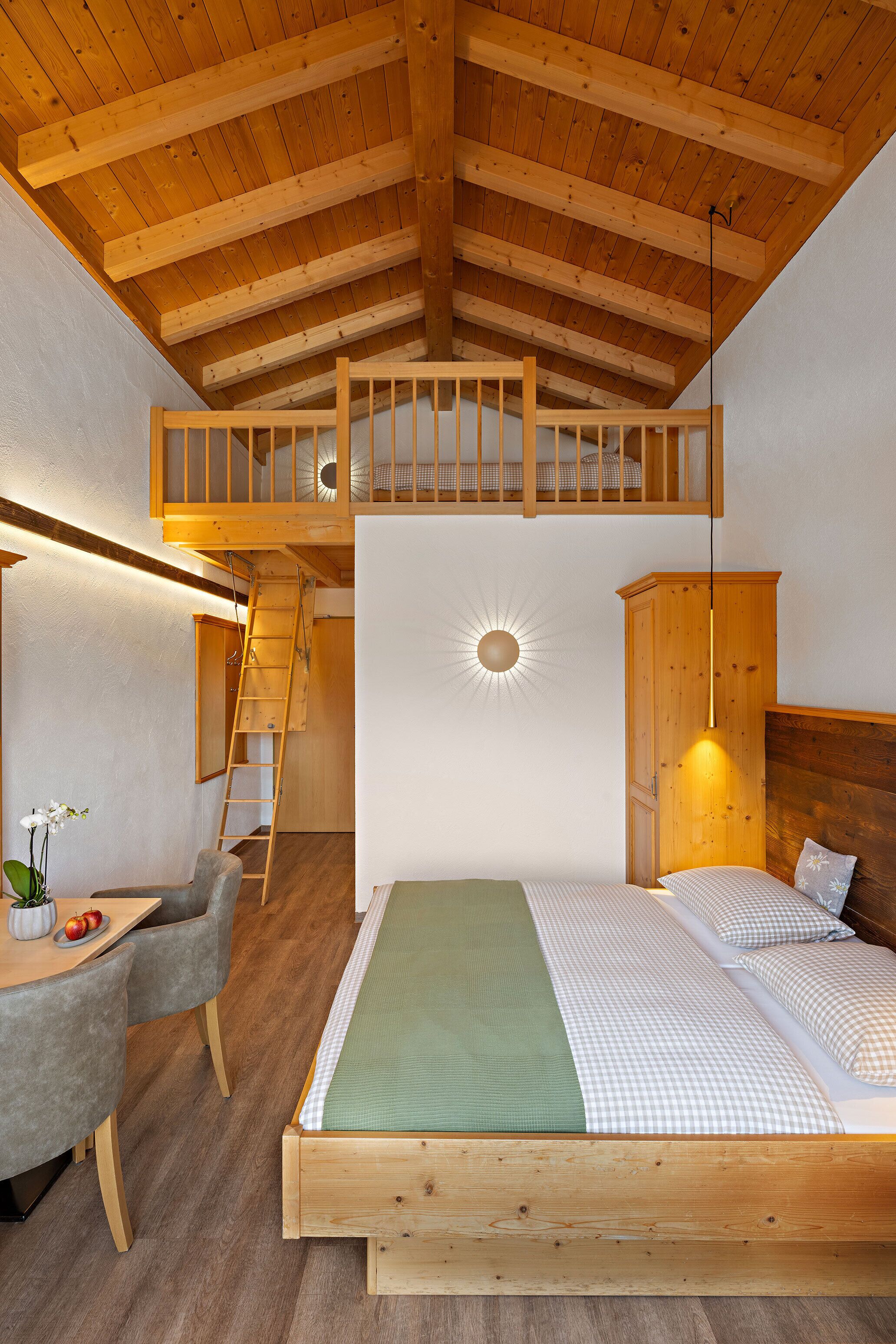 Quarto estilo loft com teto de madeira, beliche, escrivaninha com cadeira e escada para o belo superior.