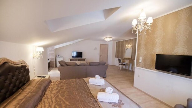 Quarto de hotel com uma cama grande, televisão, sofá e escrivaninha.