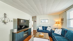 Uma sala de estar com televisão, sofá azul, mesa de centro de madeira e lareira.