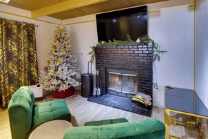 Sala de estar com lareira, sofás verdes e árvore de Natal.