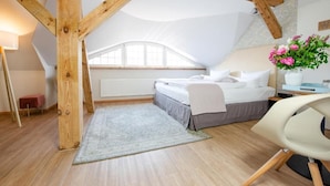 Quarto com teto inclinado, uma cama, uma escrivaninha e uma cadeira.