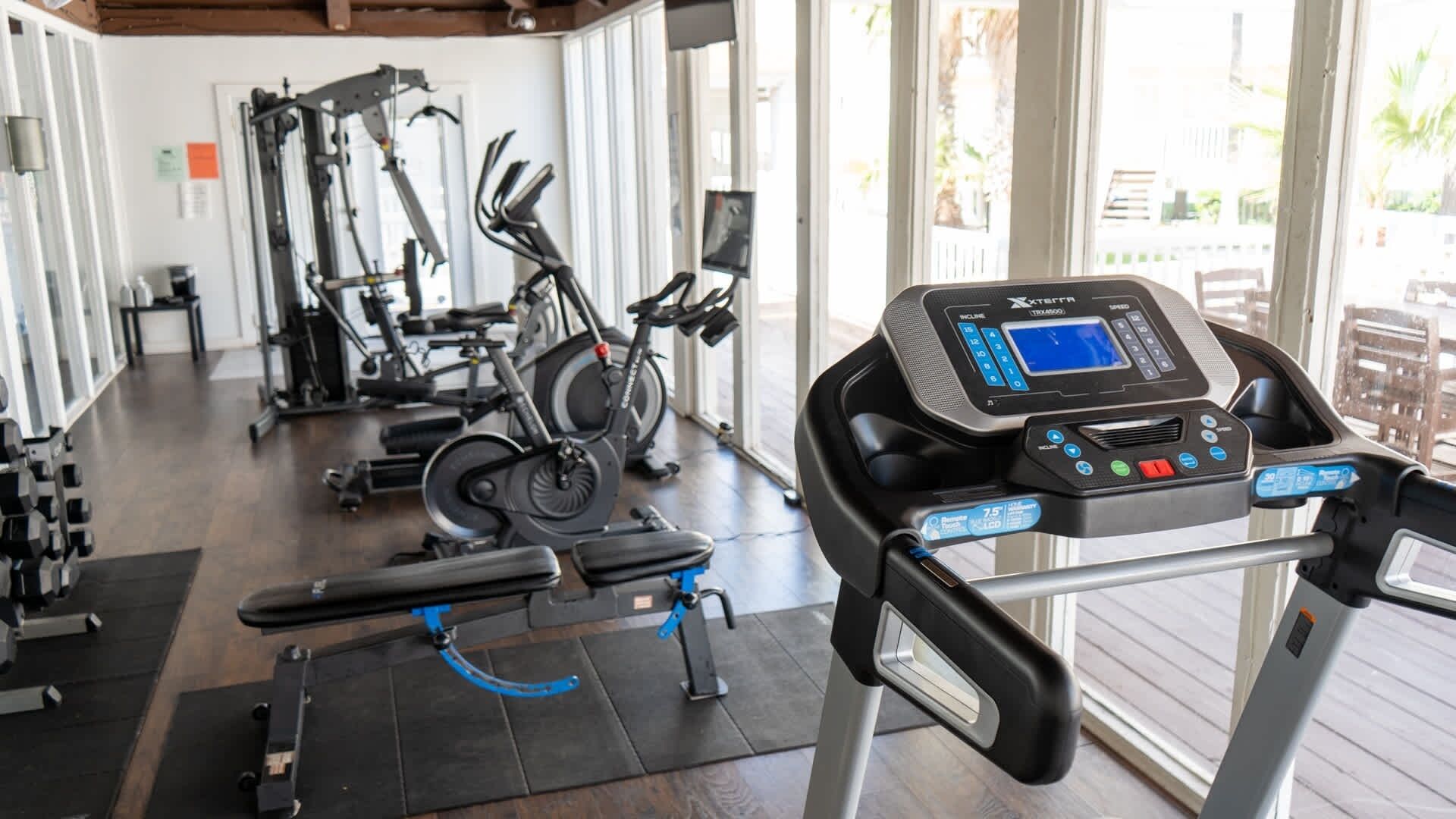 Uma academia com máquinas de cardio, equipamentos de peso e esteira com visor digital.
