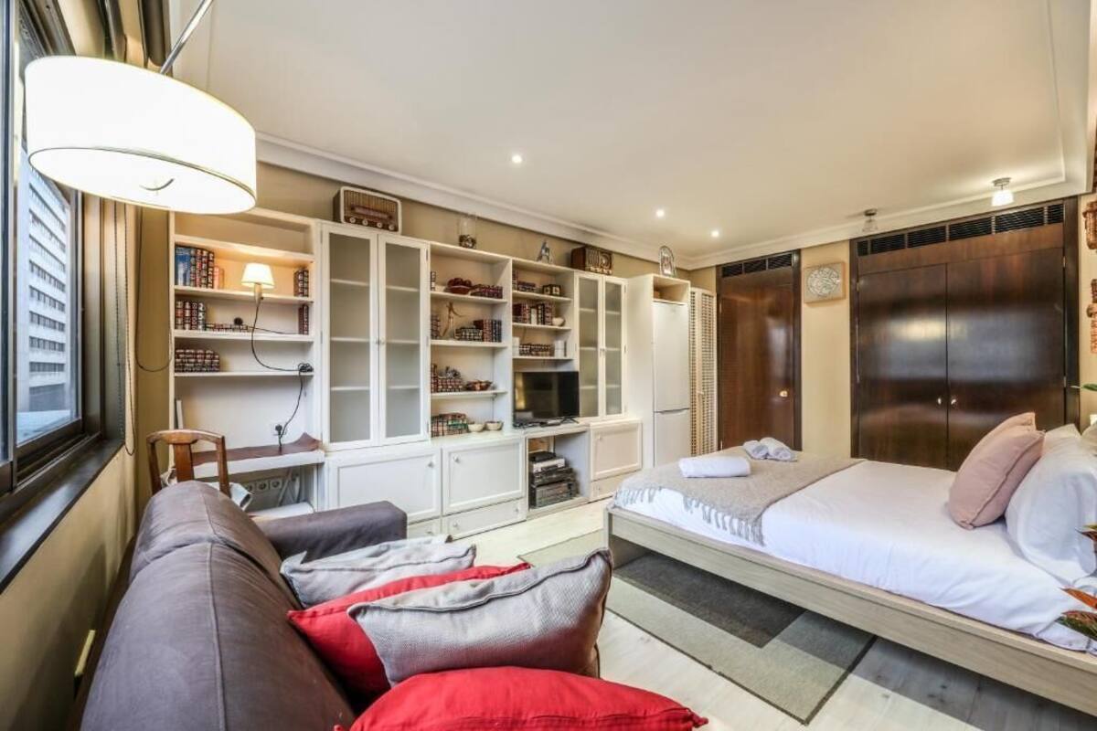 Quarto compacto com cama, sofá e armários embutidos.