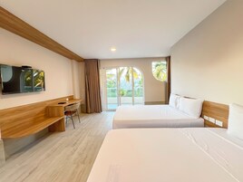 Quarto de hotel moderno com uma cama grande, uma escrivaninha e uma televisão.