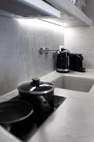 Uma cozinha com fogão, chaleira e cafeteira em uma bancada.
