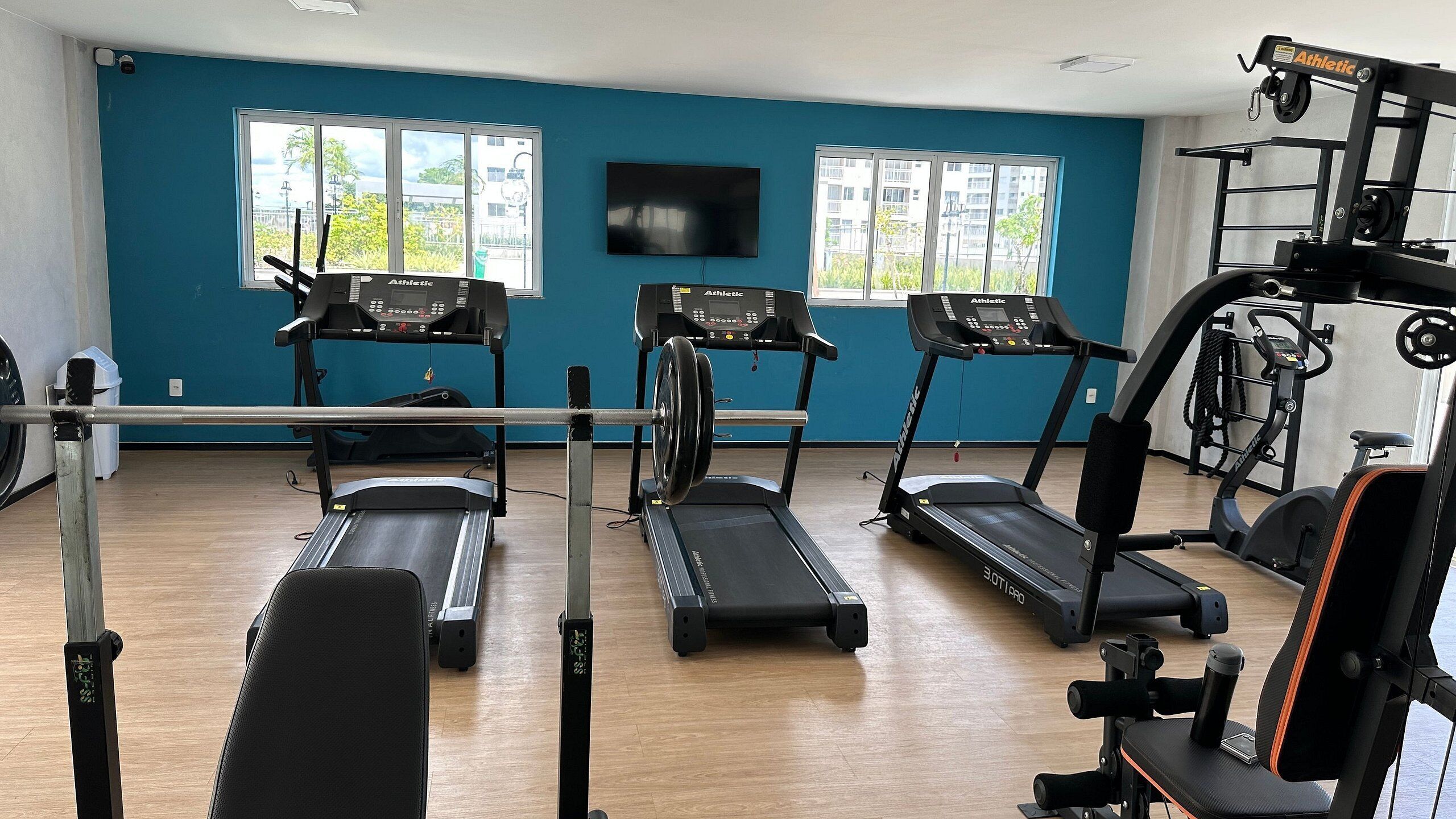 Uma academia com esteiras, um banco de musculação e equipamentos de ginástica.