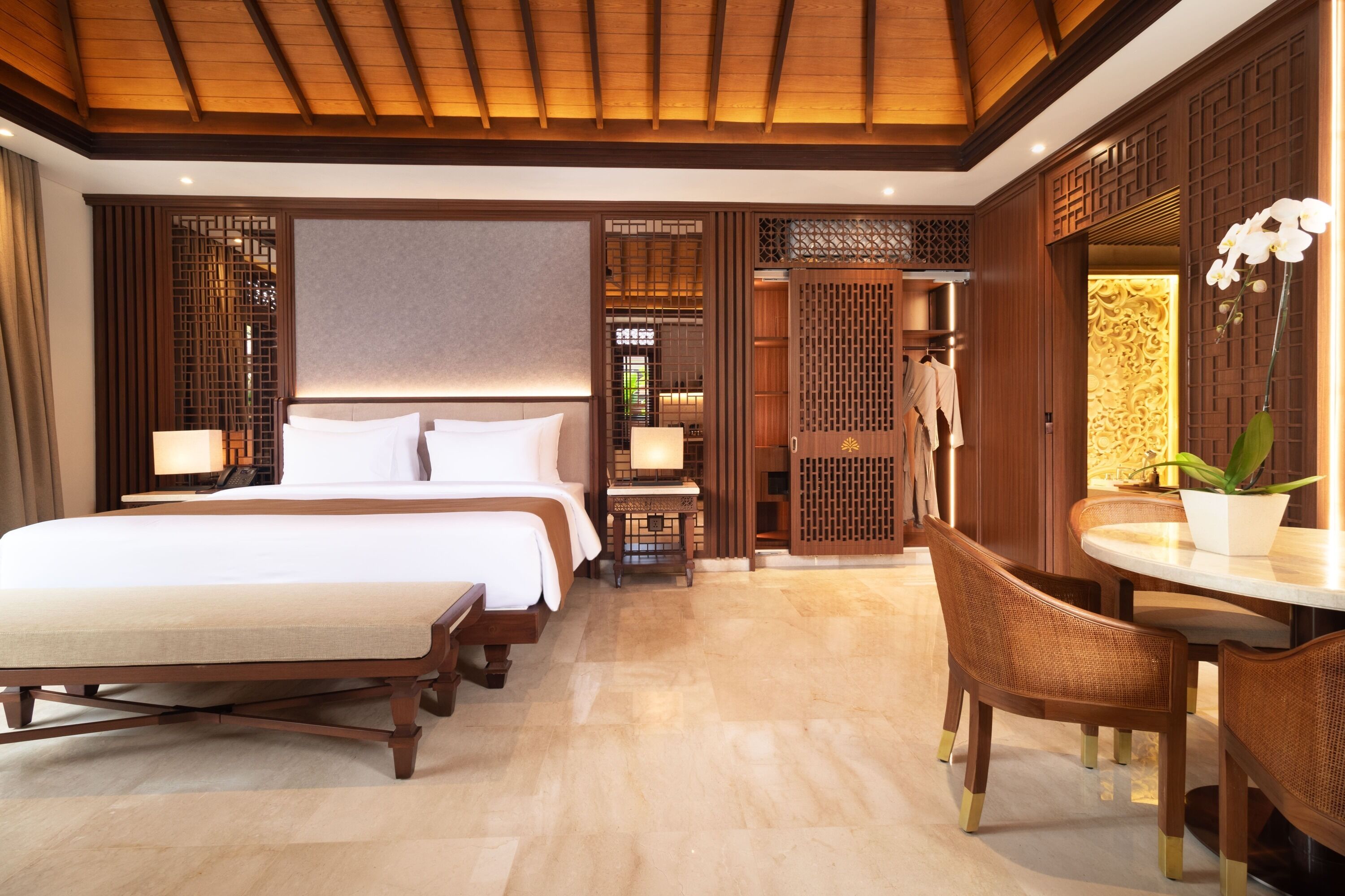 Quarto de hotel com uma cama grande, uma escrivaninha com cadeira e um painel decorativo na parede.