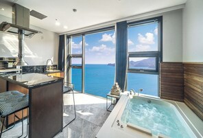 Uma casa de banho moderna com uma banheira grande, chuveiro e vista para o mar.