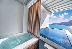 Um banheiro moderno com hidromassagem, painéis de madeira e vista para o mar.