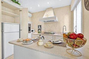 Uma cozinha com ilha central, micro-ondas, fogão e pia.