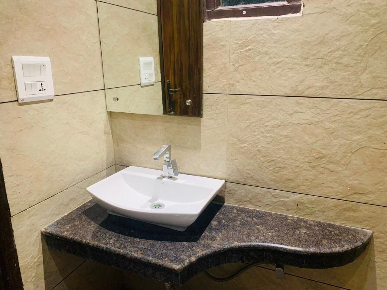 Casa de banho com lavatório branco, espelho e porta de madeira.
