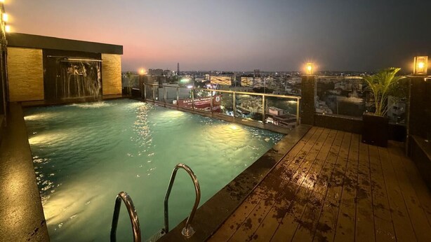 Piscina no terraço com vista para a cidade, cascata e deck de madeira.