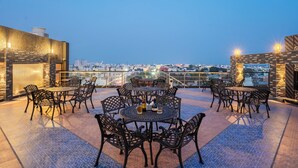 Terraço no telhado com área de estar externa, vista para a cidade e estilo arquitetônico moderno.