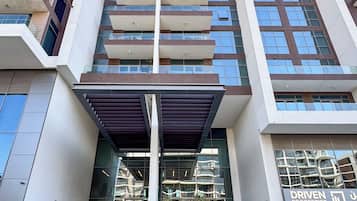 Um edifício moderno com fachada de vidro, vários andares e uma entrada central com degraus.