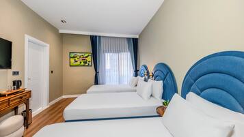 Quarto de hotel com duas camas, uma mesa com cafeteira, televisão e janela com cortinas.