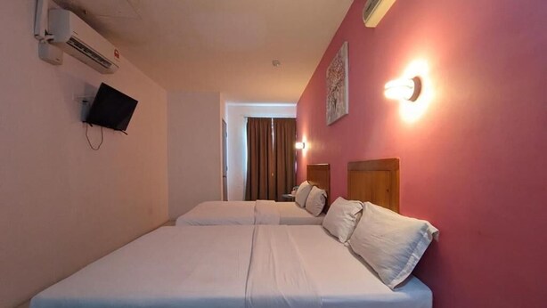 Quarto de hotel com duas camas, televisão e luz acoplada na parede.