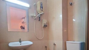 Uma casa de banho pequena com uma sanita, chuveiro e lavatório branco.