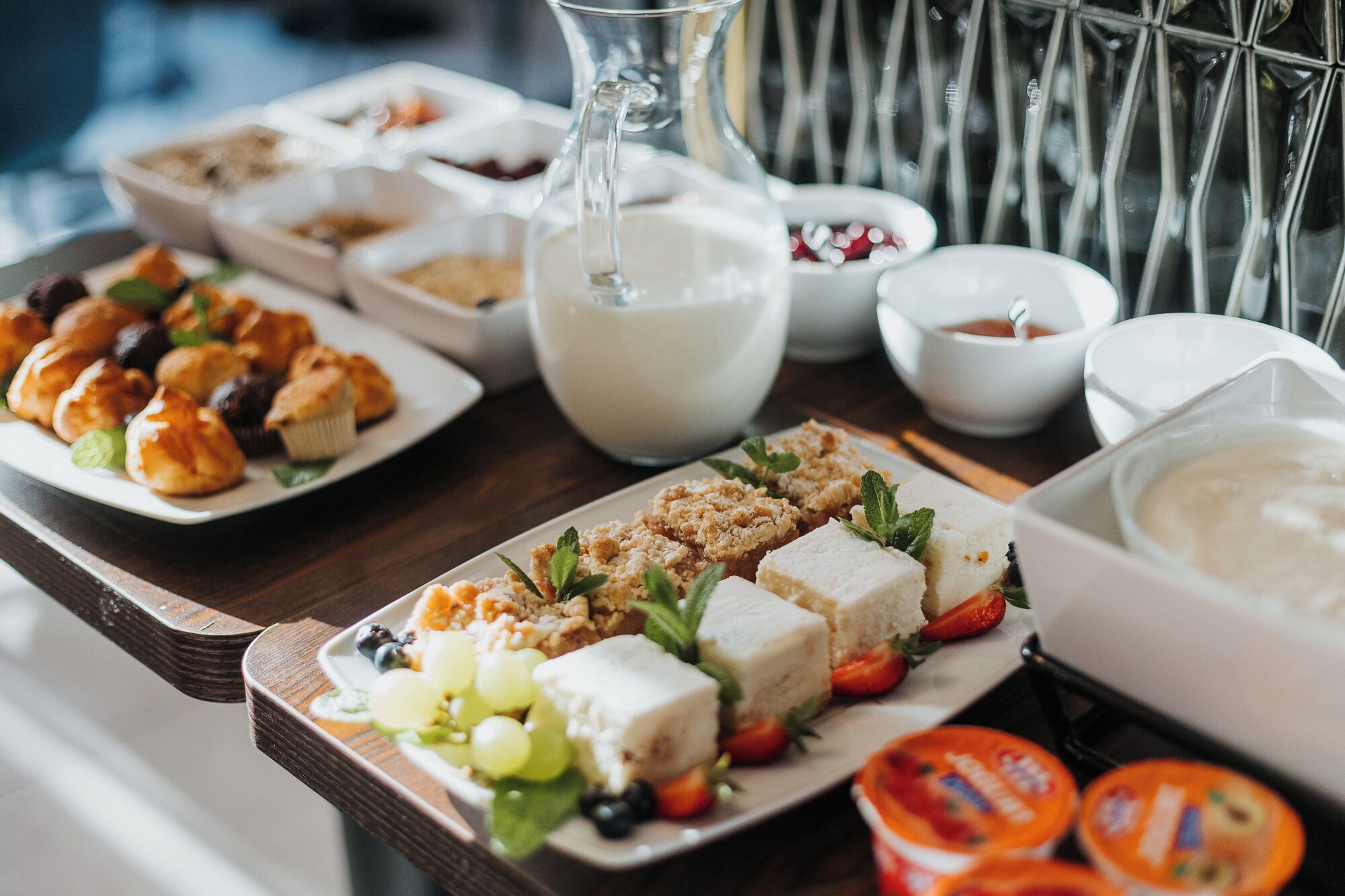 Uma mesa com diversos alimentos e acompanhamentos, incluindo doces, queijo e frutas.