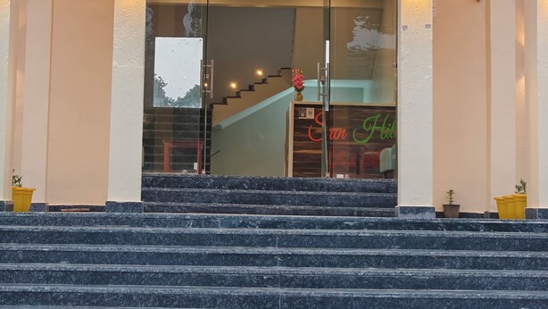 Entrada de edifício com escadaria que leva a uma porta com painel de vidro.
