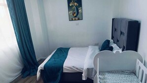 Quarto pequeno e bem arrumado com uma cama de solteiro, um berço e uma obra de arte pendurada na parede.
