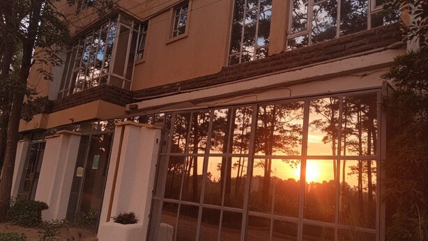 Edifício com amplas janelas refletindo o pôr do sol.