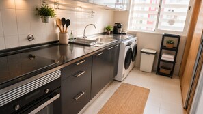Cozinha moderna com máquina de lavar embutida, pia e janela com vista para edifícios.