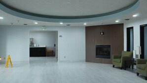 Um quarto espaçoso com parede de painéis de madeira, lareira e poltronas estofadas em verde.