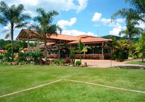 Um hotel com telhado de telhas vermelhas, rodeado por vegetação exuberante e palmeiras.