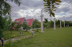 Um jardim bem cuidado com um caminho que leva a um edifício com telhado vermelho.
