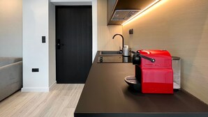 Uma cozinha moderna com máquina de café expresso integrada, pia e porta escura.
