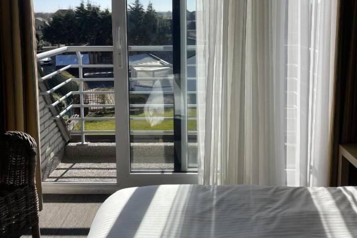 Quarto de hotel com uma cama grande, vista para uma varanda e uma porta de vidro deslizante.
